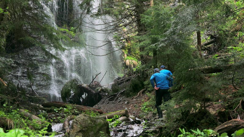 Wilderness Explorers Approaching a Breathtaking Waterfall in a Secluded ...