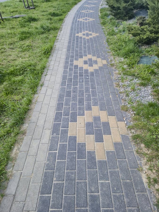 A Winding Pathway Made of Patterned Bricks in a Lush Green Park Setting ...