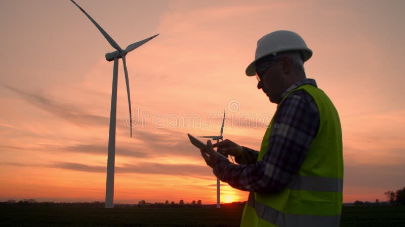 Windmill Engineer Watching Wind Turbines in Operation on a Tablet Stock ...