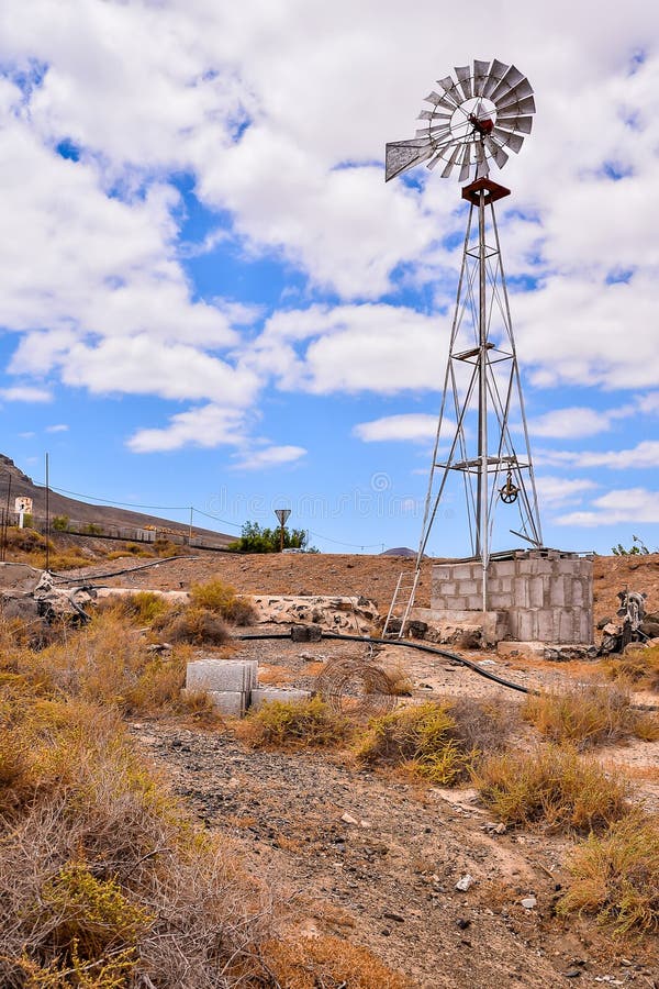 A Windmill is Standing in a Field with a Blue Sky in the Background ...