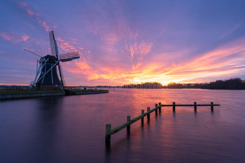 Windmill sunset at a lake stock photo. Image of meteorology - 238779682