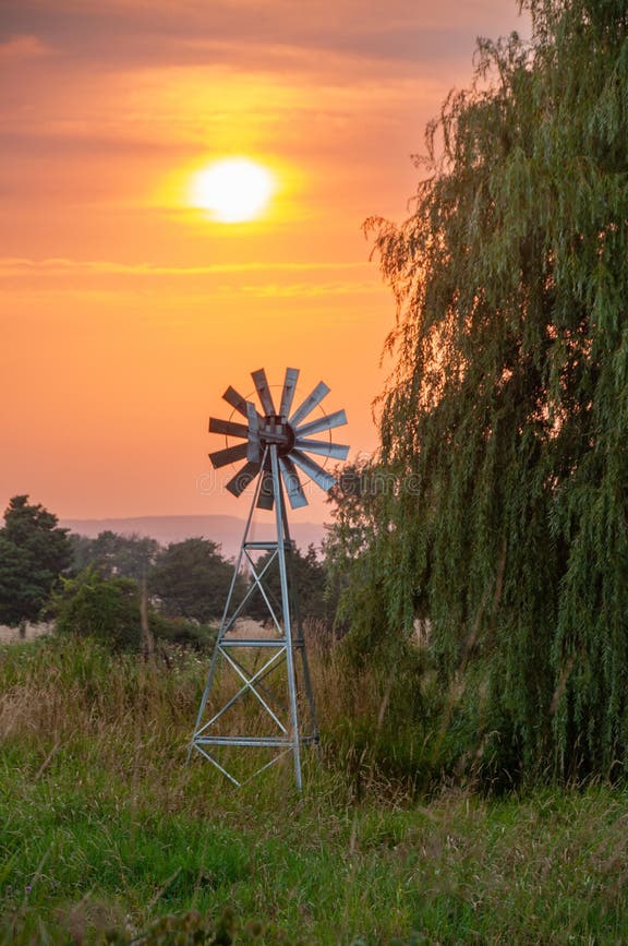 A Windmill beside a Willow Tree during a Stunning Sunset Stock Photo - Image of technology ...
