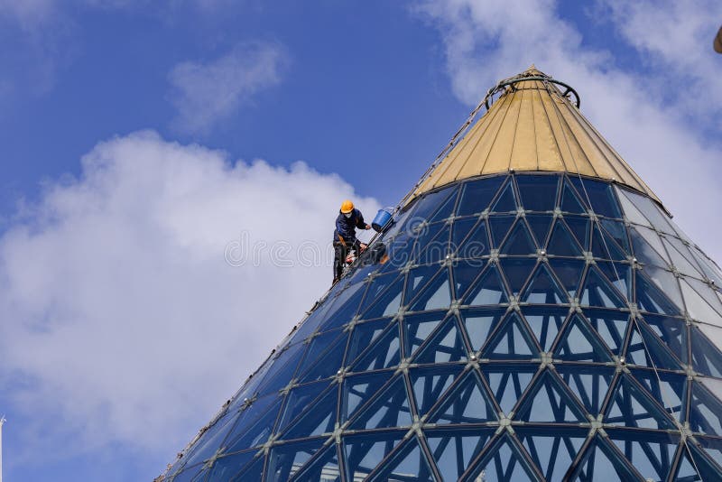 Window Cleaner on a Modern Glass Pyramid Structure Against a Bright ...