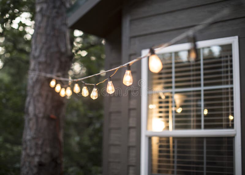 String of Patio Lights Glowing Warmly at Dusk As the Woods Grow Dark ...