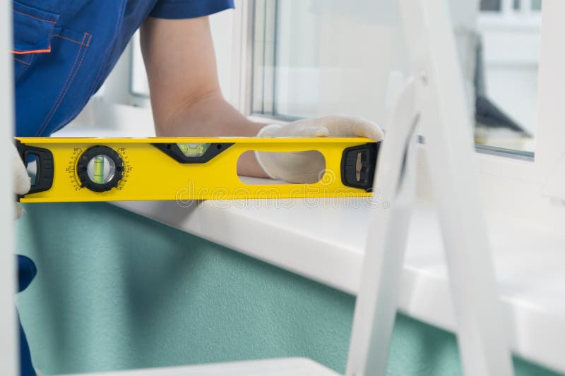 A Window Installation Worker Checks the Level of the Window Sill with a ...