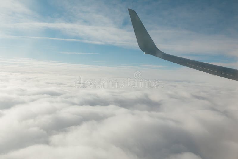 Wing of an Airplane in Flight Above Clouds in a Blue Sky Stock Photo ...