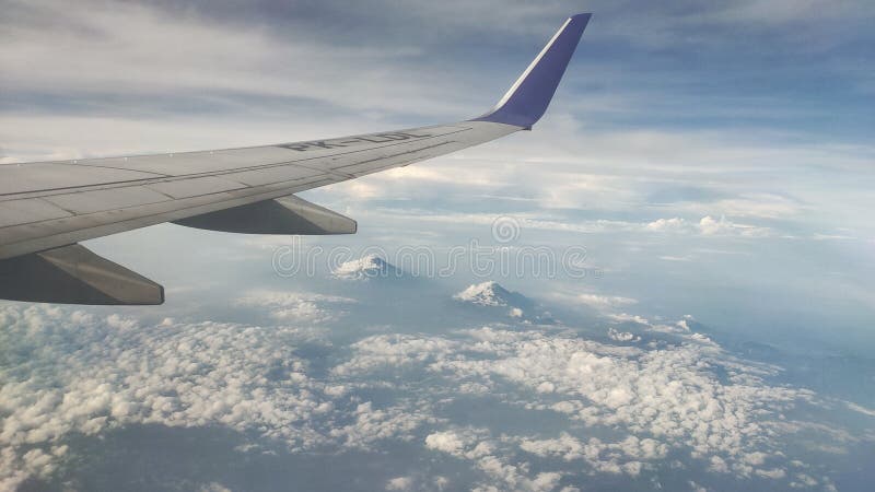 Wing of the Plane Above Clouds with the Background Mountains Stock ...