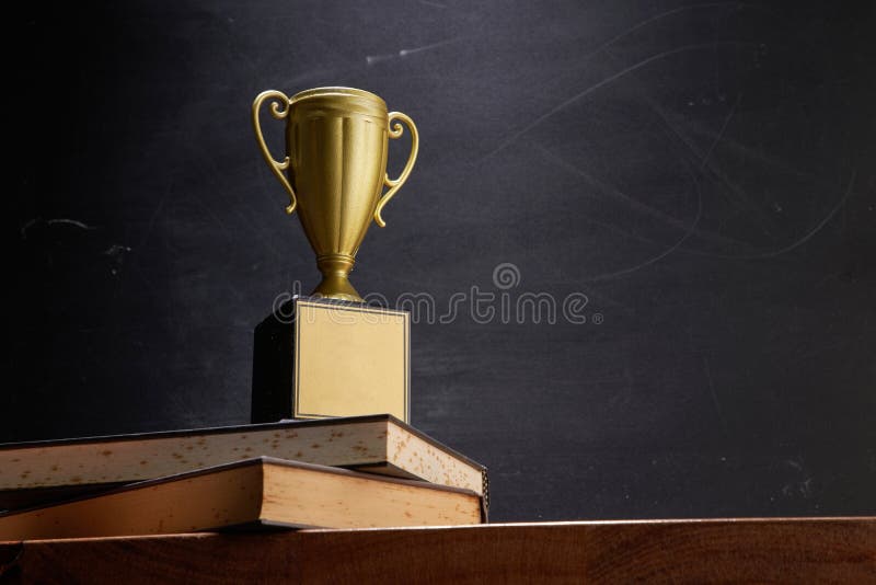 Wining Trophy on Stack of Book Against Blackboard Stock Photo - Image ...