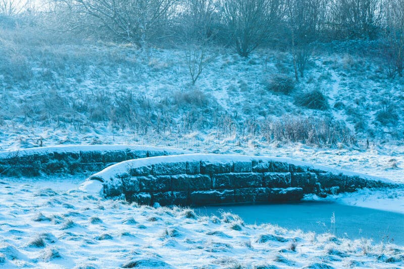 A Wintery Scene Showing a Snow Covered Bridge Over a Frozen River Stock ...