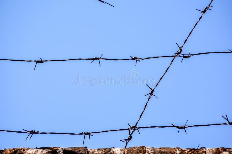 A Wire Fence with Barbed Wire on Top of it Stock Photo - Image of ...