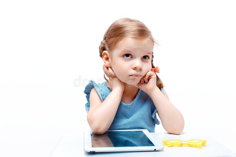Wishful Thinking Young Girl is Using Tablet while Sitting at Table ...