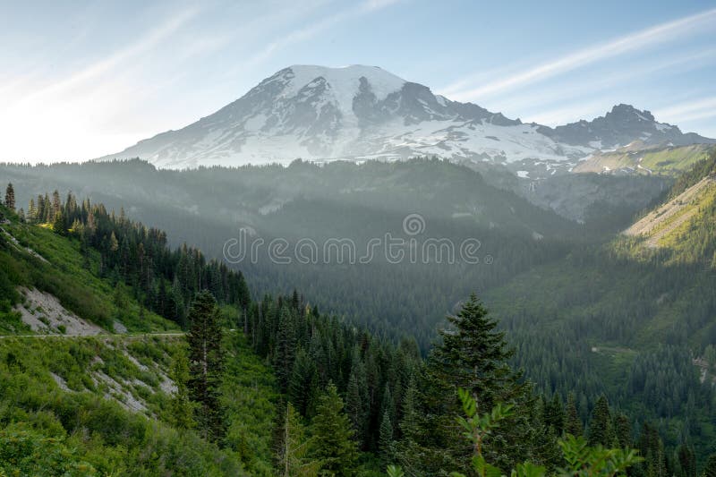Wisps of Clouds Pass Over Mount Rainier with Light Rays Passing in Front of the Mountain Stock ...