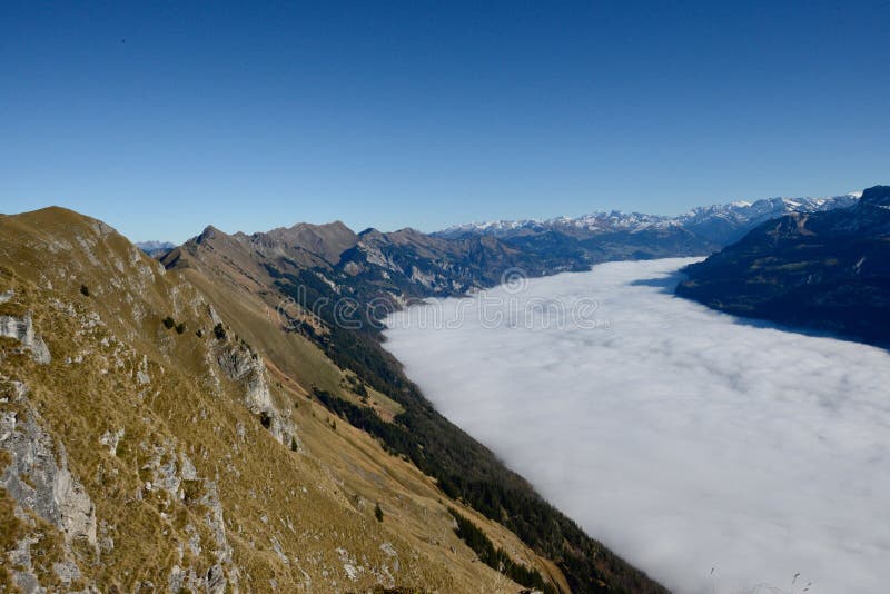 Wispy Clouds Cascading Down the Rugged Slopes of a Mountain Range at ...