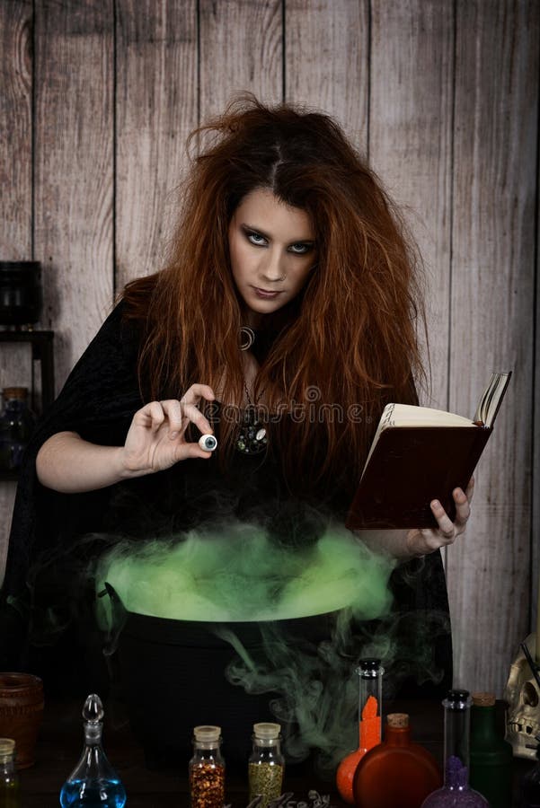 Witch Pouring Poison into Her Magic Potion with Skull in Fog Stock ...