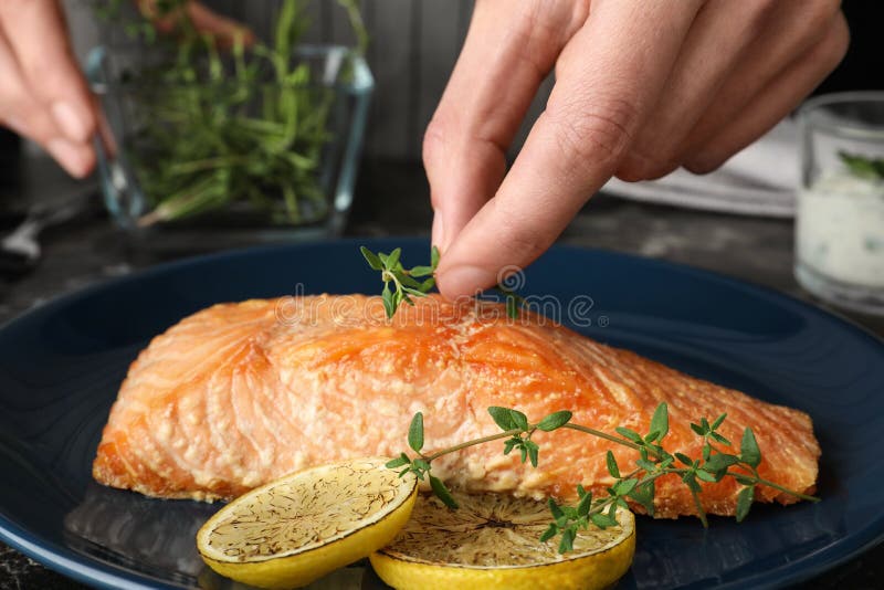 Woman Adding Thyme To Cooked Red Fish on Table, Closeup Stock Image ...