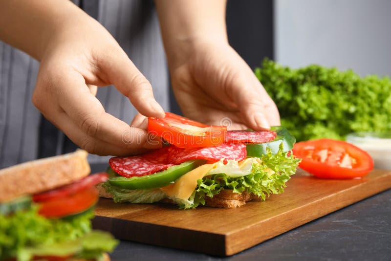 Woman Adding Tomato To Sandwich at Black Table Stock Photo - Image of ...
