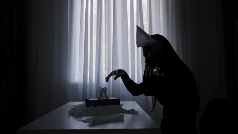 Silhouette of Woman Sitting at Table in Front of Window, Crying ...