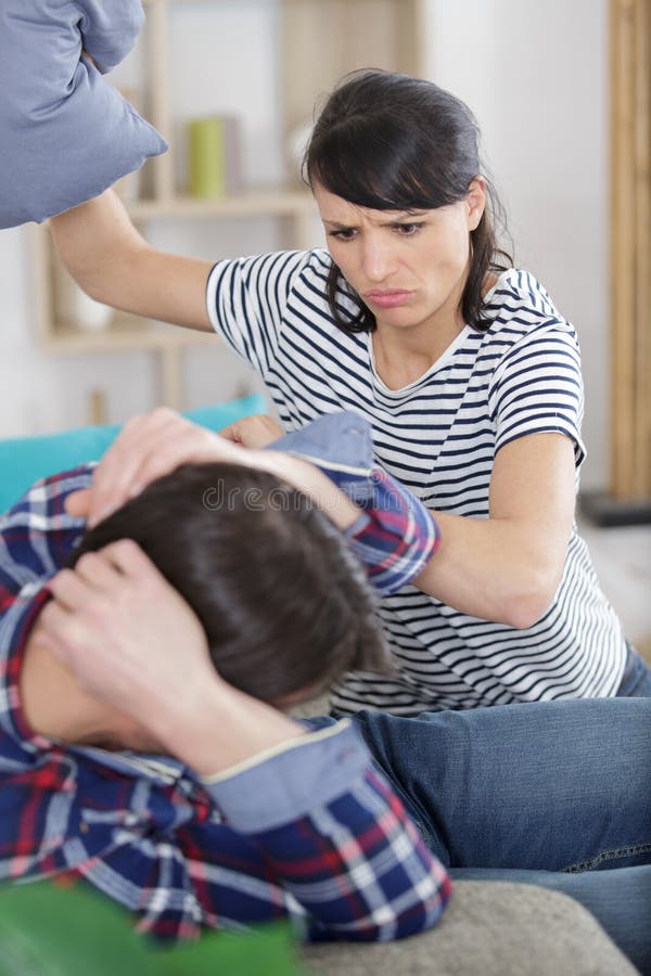 Woman Angrily Hitting Boyfriend with Cushion Stock Photo - Image of ...