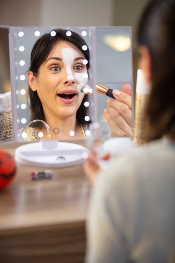 Woman Applying Face Paint Looking at Reflection with Surprise Stock ...
