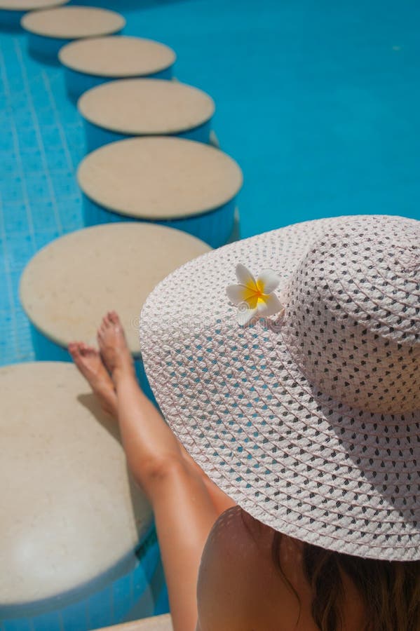 Woman in a Big White Hat Sits on the Edge of the Pool with Stones Stock ...