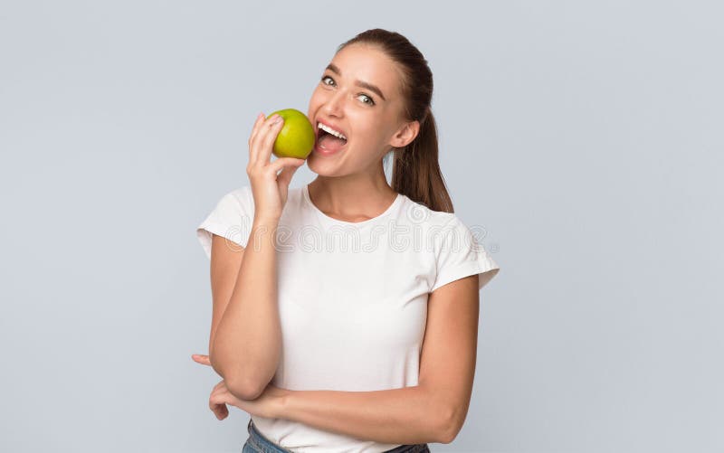 Woman Biting Apple Looking at Camera Standing in Studio Stock Image ...