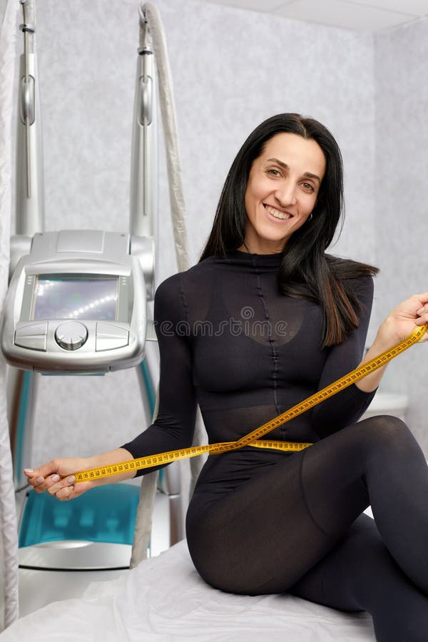 Woman In A Black Suit For Lpg Massage Holds A Centimeter In Her Hands