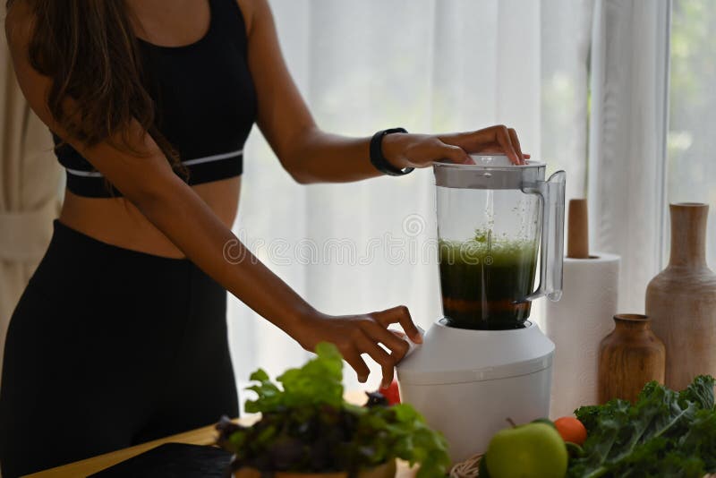 Woman With Blender Making Healthy Green Smoothie In The Kitchen