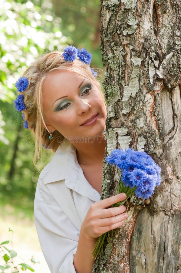 Woman with Blue Flowers Peeking from Behind a Tree Stock Image - Image ...