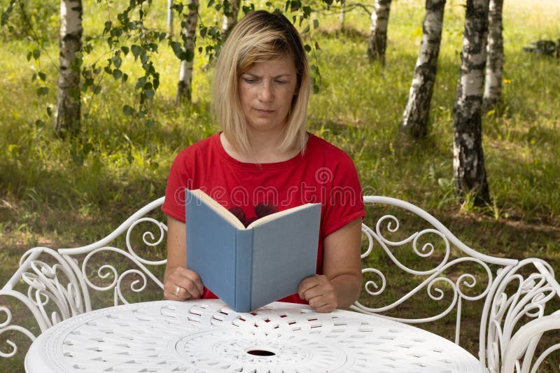 A Woman with a Book at the Table. a Woman is Reading a Book Stock Photo ...