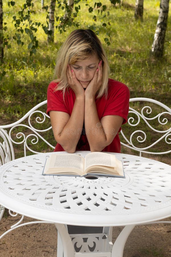 A Woman with a Book at the Table. a Woman is Reading a Book Stock Photo ...
