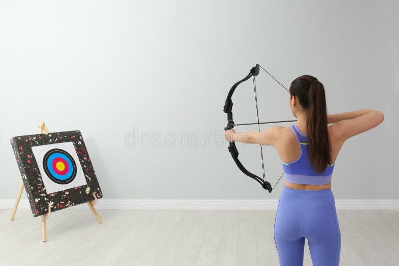 Woman with Bow and Arrow Aiming at Archery Target Indoors, Back View ...