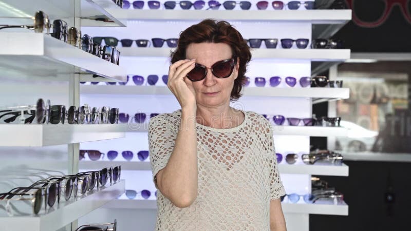 Woman Browsing Sunglasses, Surrounded by Diverse Styles, Trying on ...