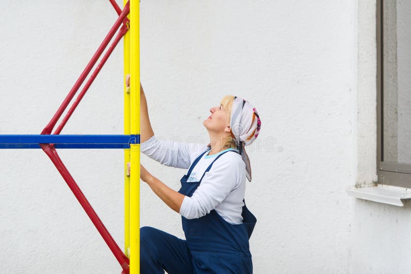 Woman in Builder Uniform Rises on a Construction Ladder. Stock Image ...