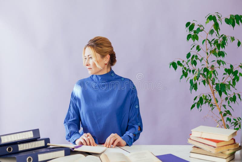 Woman in Business Suit at the Desk at Work in the Office with Books ...