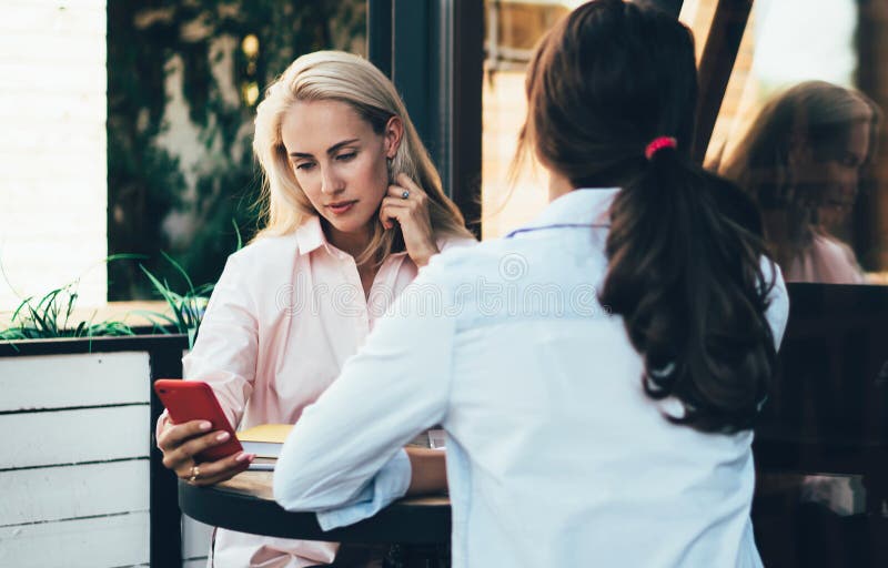 Woman at Cafe with Female Friend Using Phone Stock Photo - Image of ...