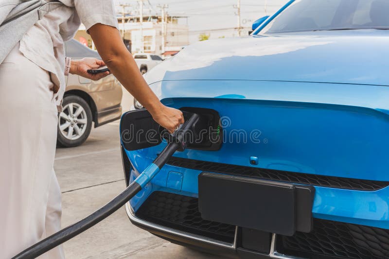 Woman Charging at Electric Vehicle at Charging Station and Paying ... Woman Charging at Electric Vehicle at Charging Station and Paying ...