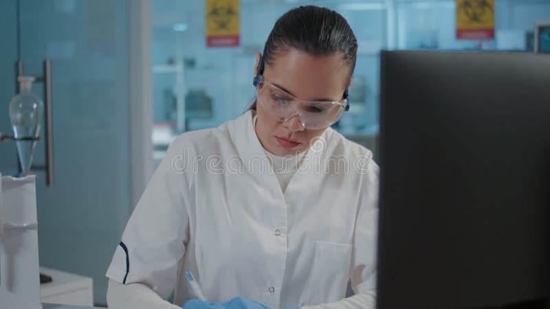Woman Chemist Taking Notes and Using Computer for Experiment Stock ...