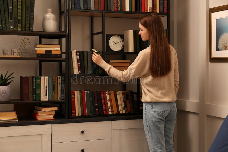 Young Woman Choosing Book on Shelf in Home Library Stock Image - Image ...