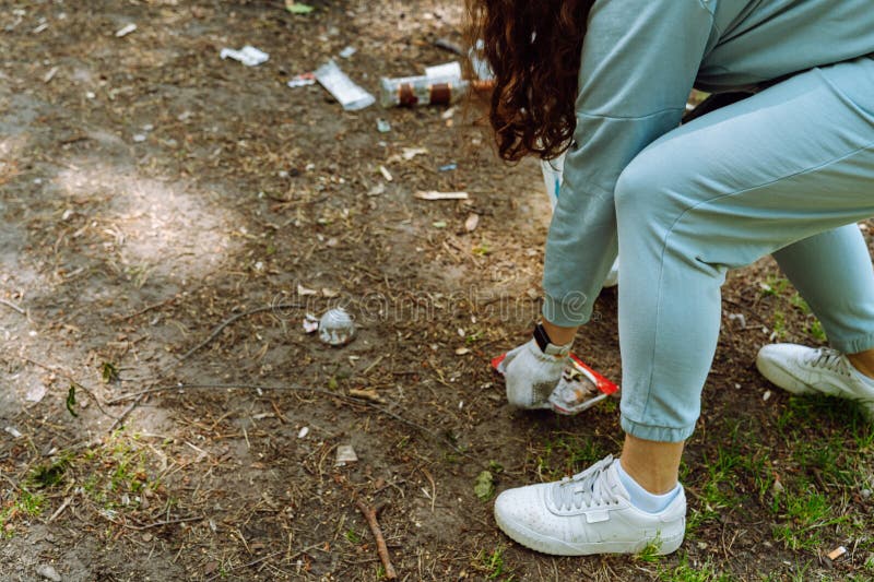 A Woman Cleans Up Garbage in a Clearing in the Forest, Left by Tourists ...