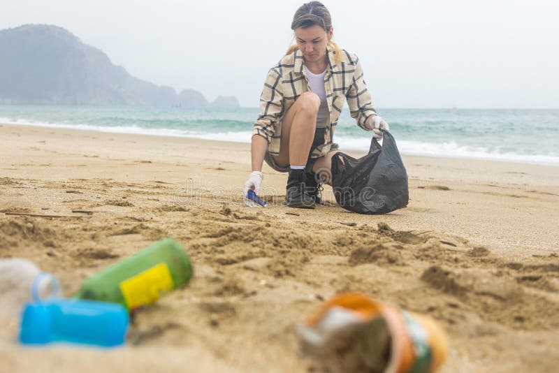 A Woman Cleans Up Trash from the Beach. Plastic Environmental Pollution ...