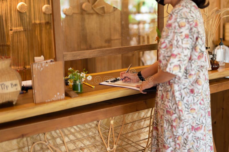 Woman Client Signing Hotel Contract Paper at Reception Desk in Face ... Woman Client Signing Hotel Contract Paper at Reception Desk in Face ...