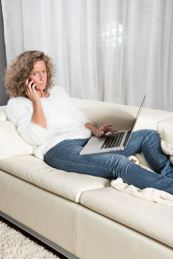Woman with Computer on Couch Having a Phone Call Stock Photo - Image of ...