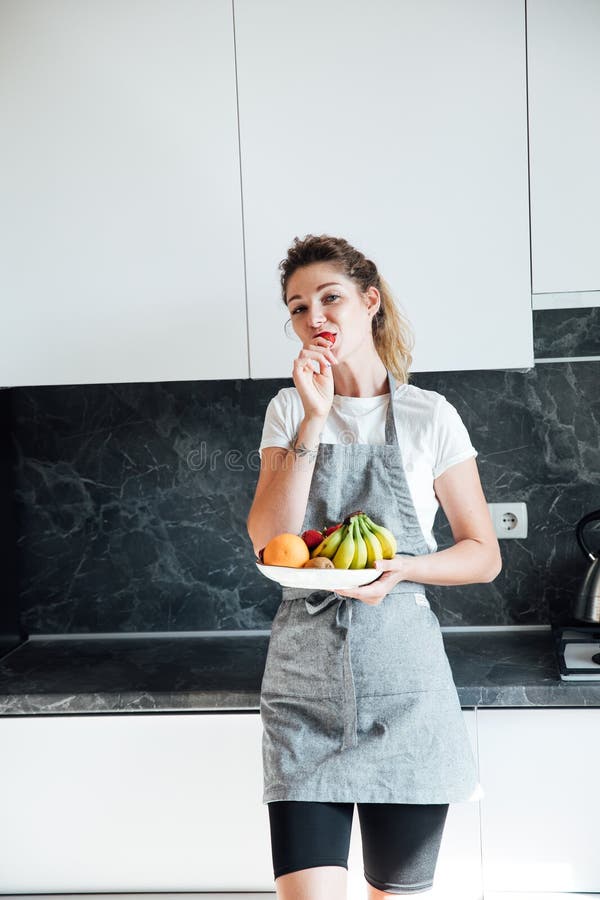 A Woman Cook in an Apron Stands with Fruit in the Kitchen Stock Photo ...