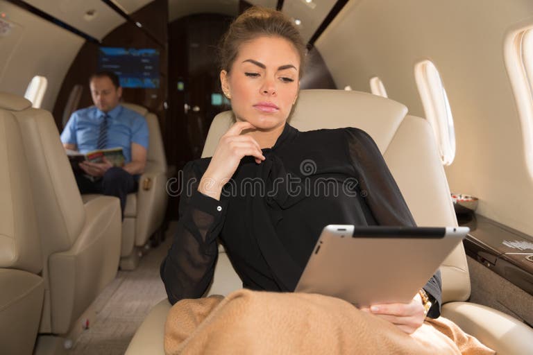 Woman in Corporate Jet Looking at Tablet Computer Stock Image - Image ...