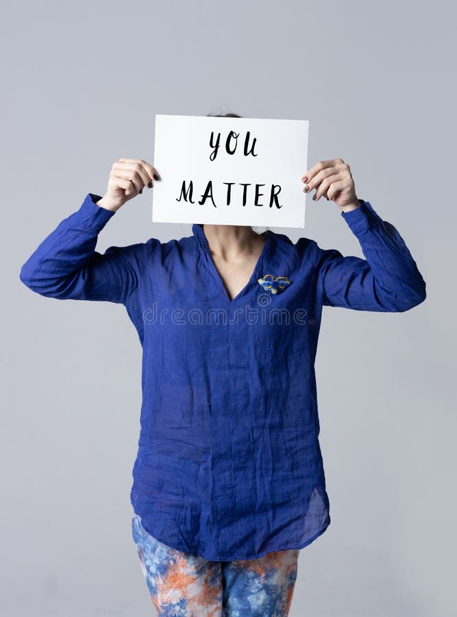 Woman Covering Her Face with a White Poster with the Words You Matter ... Woman Covering Her Face with a White Poster with the Words You Matter ...