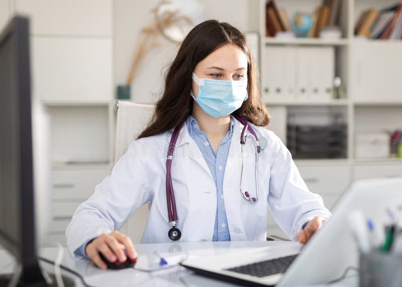Woman Doctor in Protective Mask Sitting at Workplace with Computer in ...