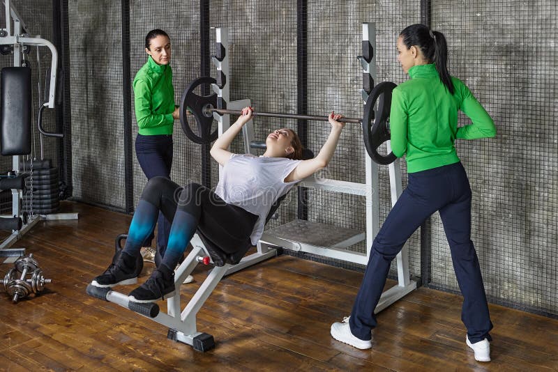 Woman Does Bench Press in Gym, she is Assisted by Trainers. Stock Image ...