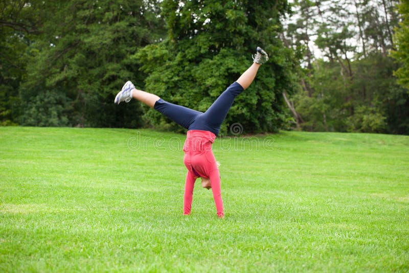 Woman doing cartwheel stock photo. Image of handstand - 24781588