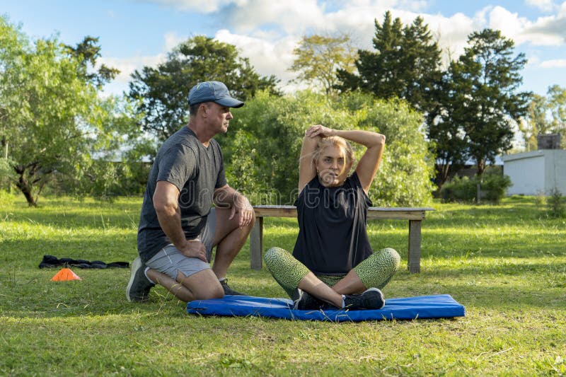 Woman Doing Stretching Exercises with Trainer in Park Setting Stock ...