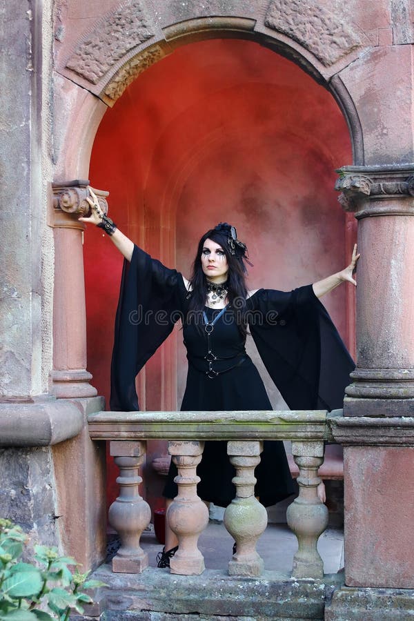 A Woman Dressed As a Witch in an Archway with Red Smoke Stock Photo ...